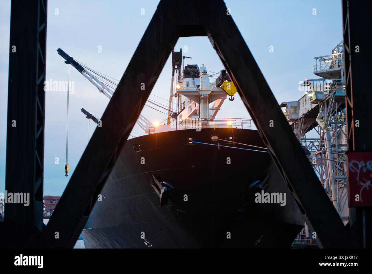Big black ocean cargo ship with cranes mounted on the deck moored in ...