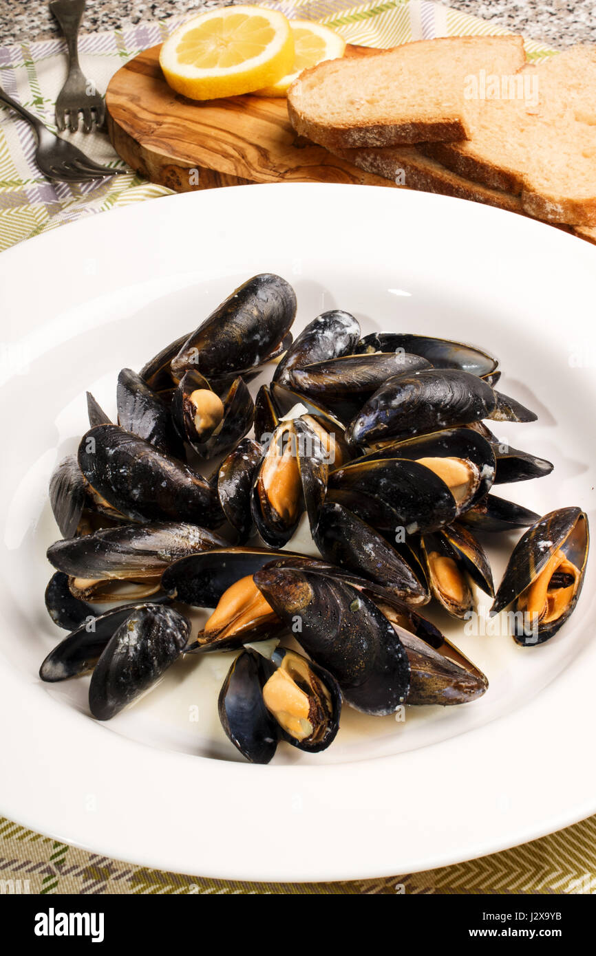mussels with garlic and butter sauce in a deep plate with bread and ...