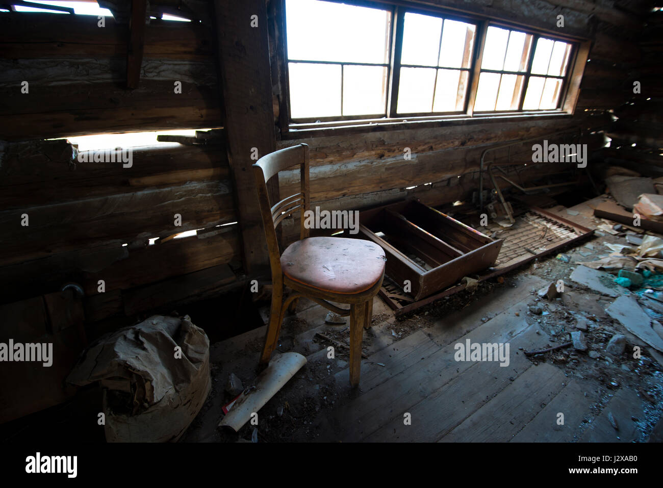 Light from a long window of an old abandoned wooden house lights ...