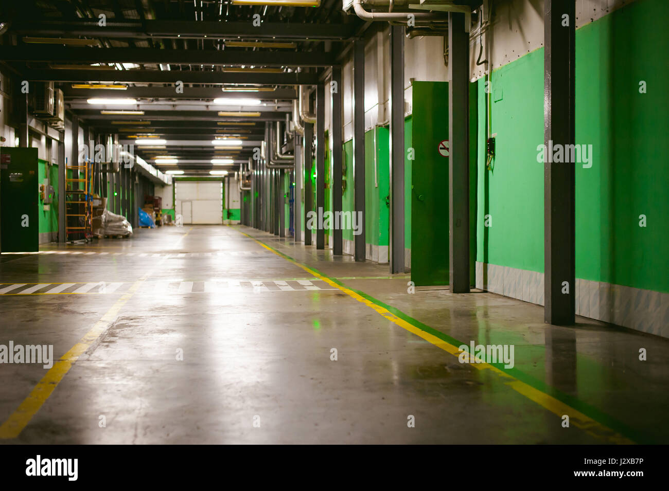 Corridor in a production building with green walls and a bulk concrete ...