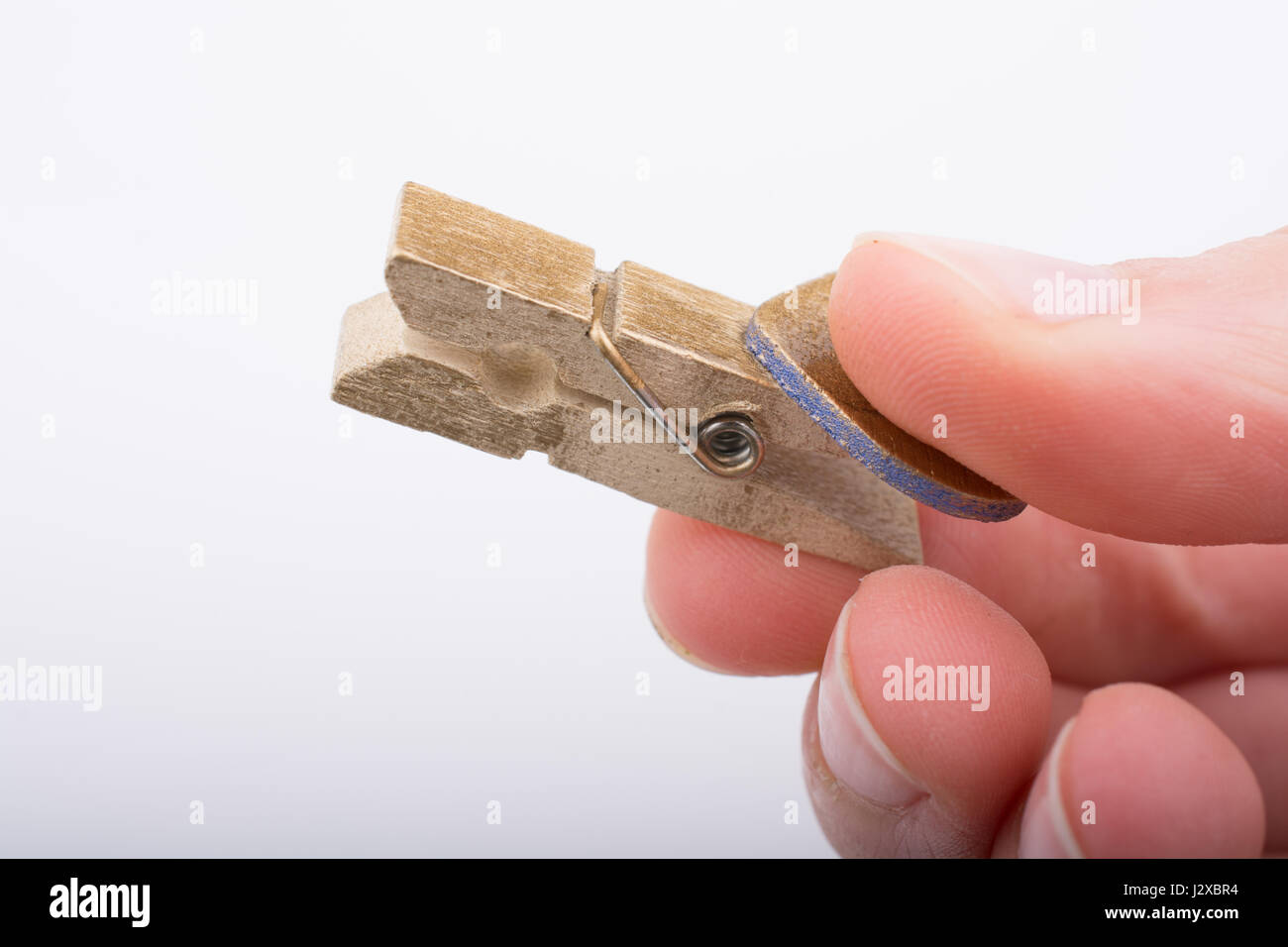 Hand holding a small wooden clothespin in hand Stock Photo - Alamy