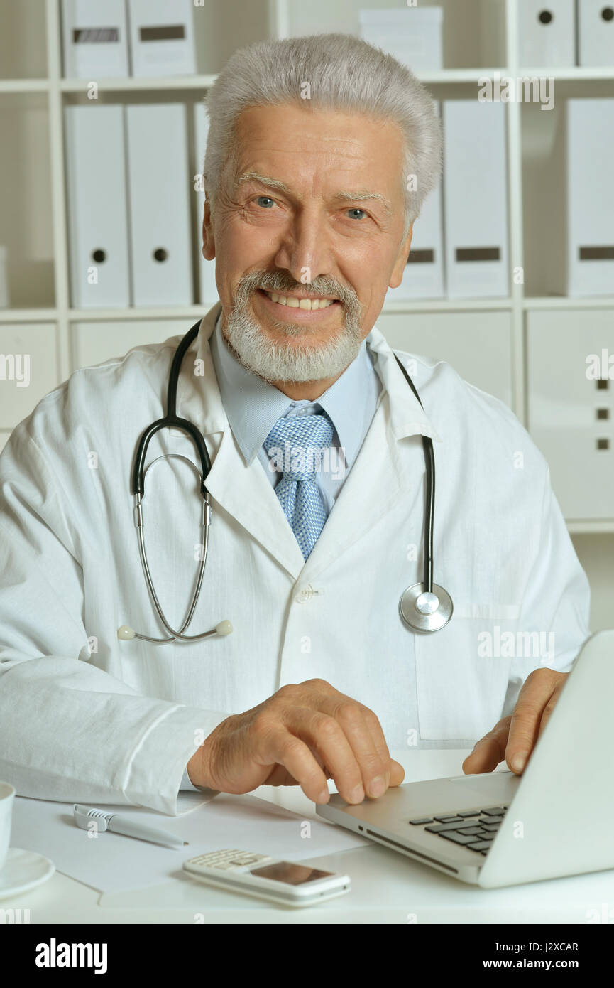 Old doctor with a laptop working Stock Photo - Alamy