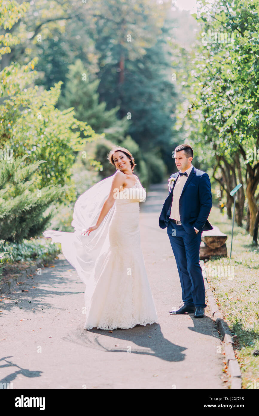 The photo of happy newlyweds. The bride in white dress is moving around ...