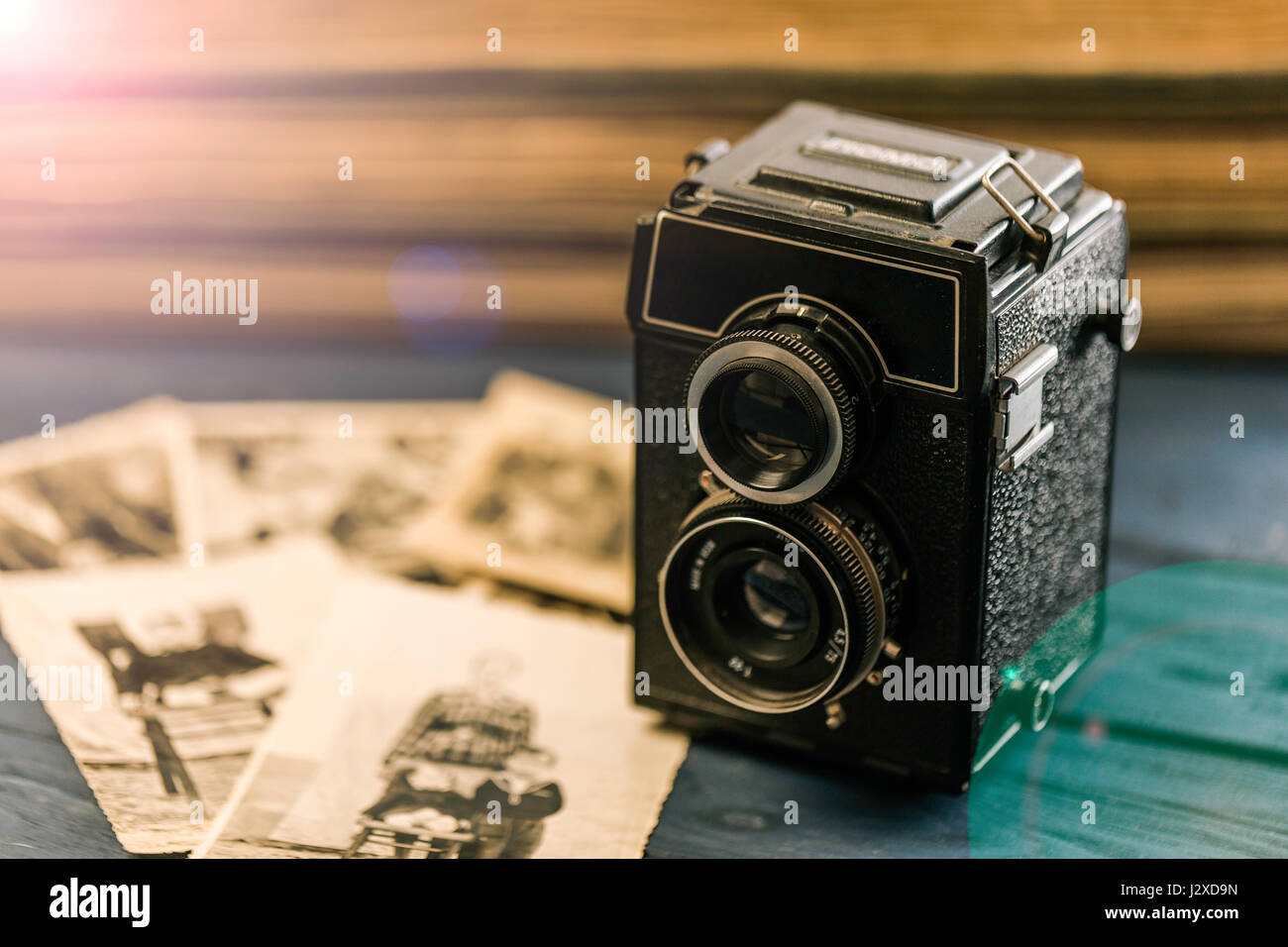 Studio shot of old vintage photo camera with pictures on wooden ...