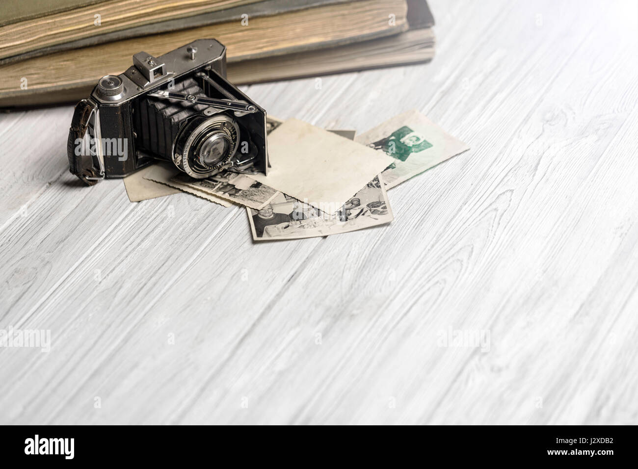 Studio shot of old vintage photo camera with pictures on wooden ...