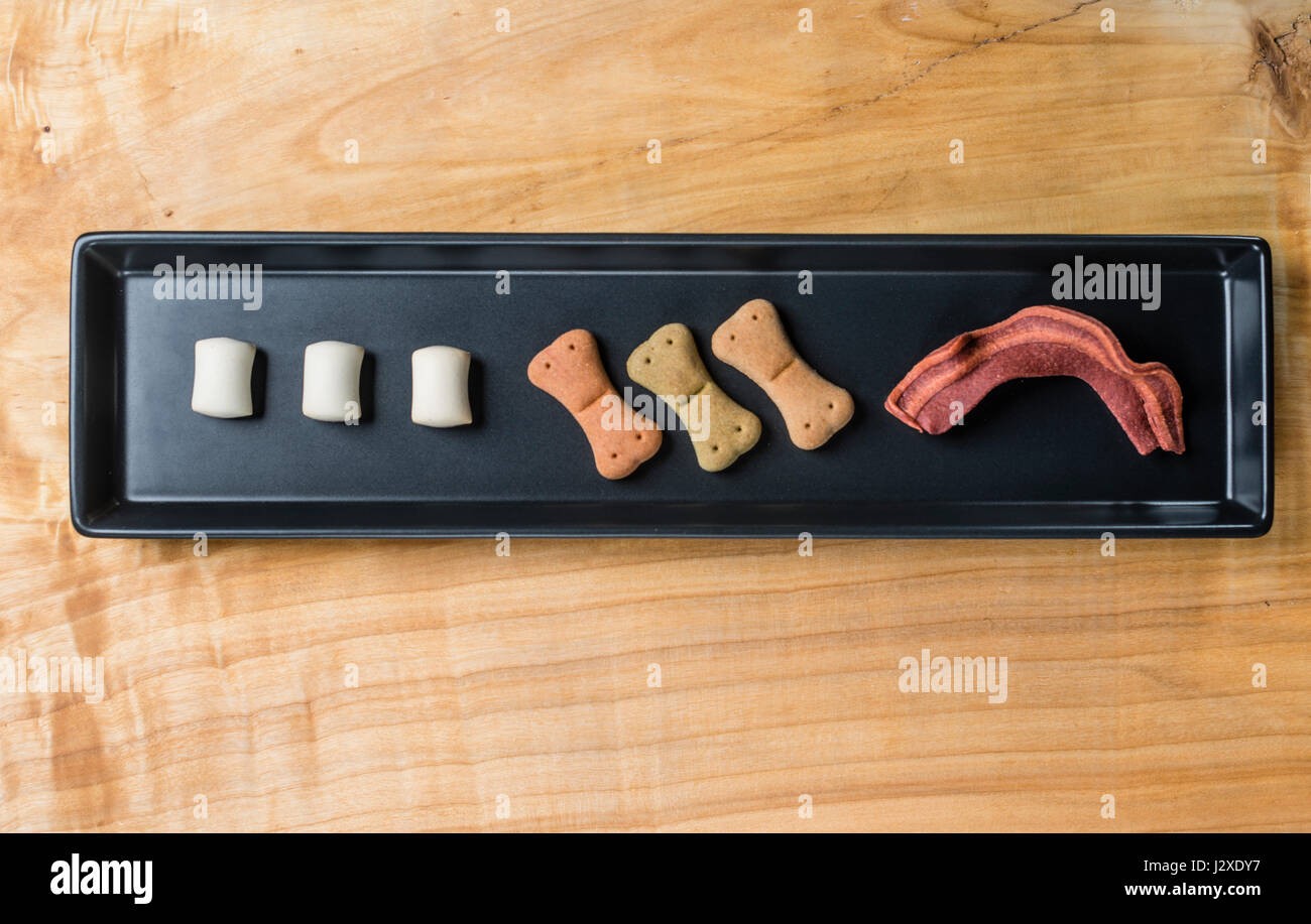 Dog food in a rectangular black dish over a wooden board served very ...