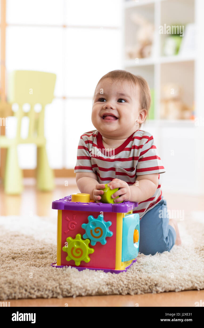 Baby toddler playing with sorter toy sitting on soft carpet at home ...