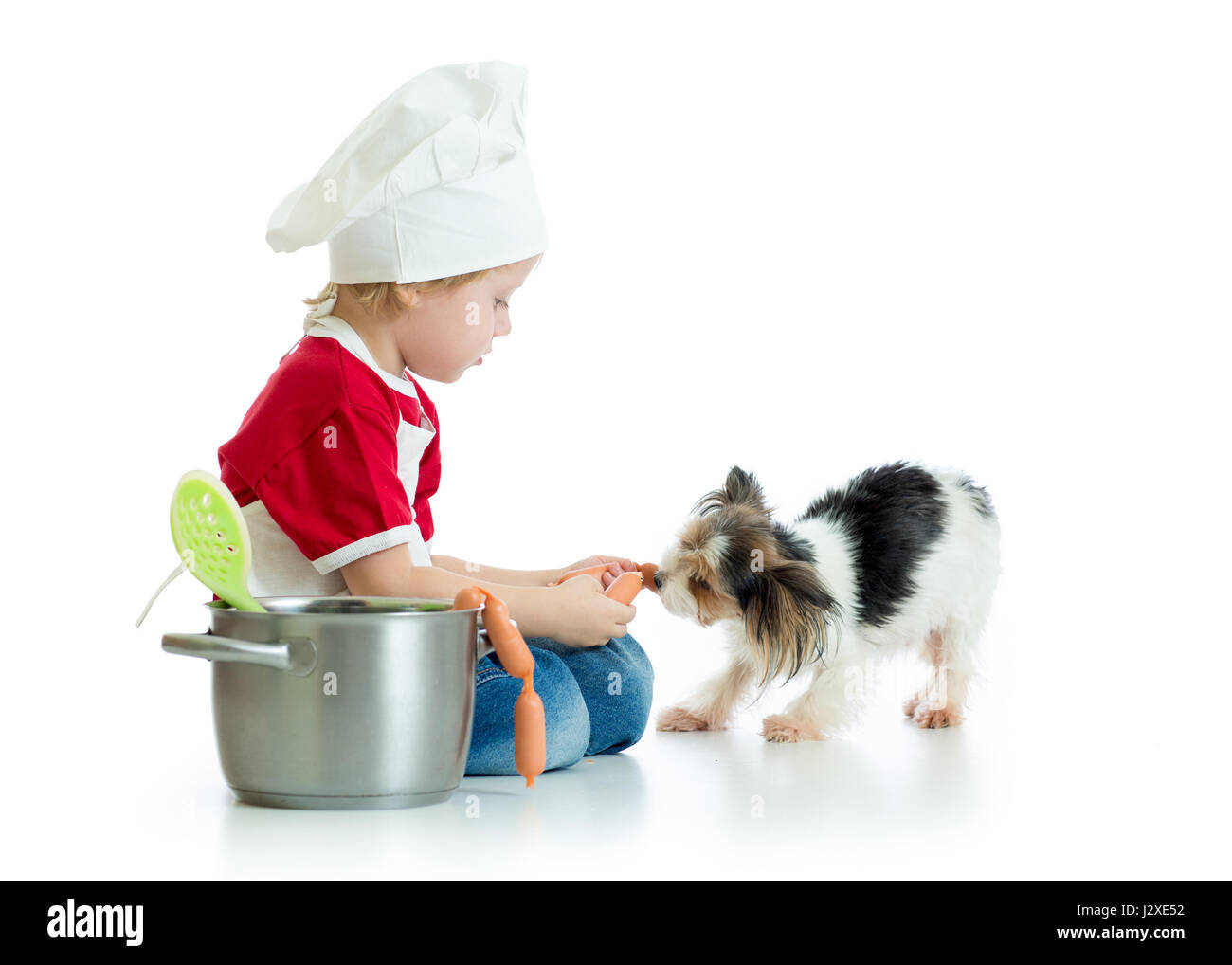 Role-playing game. Kid boy plays chef with dog. Child weared cook feeds ...