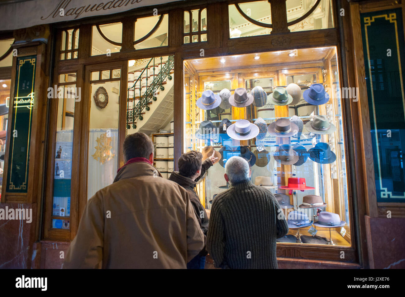 young man and elderly man in front of window of a traditional hat shop ...