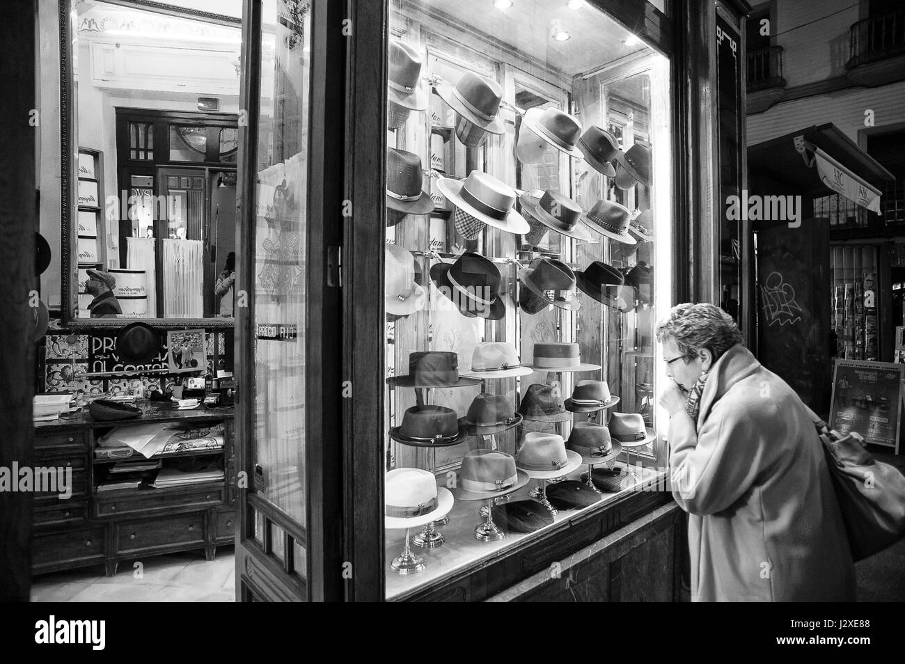 middle-aged woman in front of window of a traditional hat shop in ...