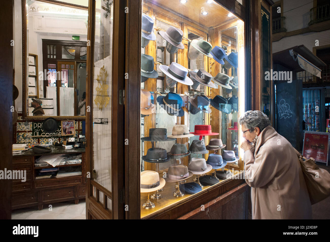 middle-aged woman in front of window of a traditional hat shop in ...