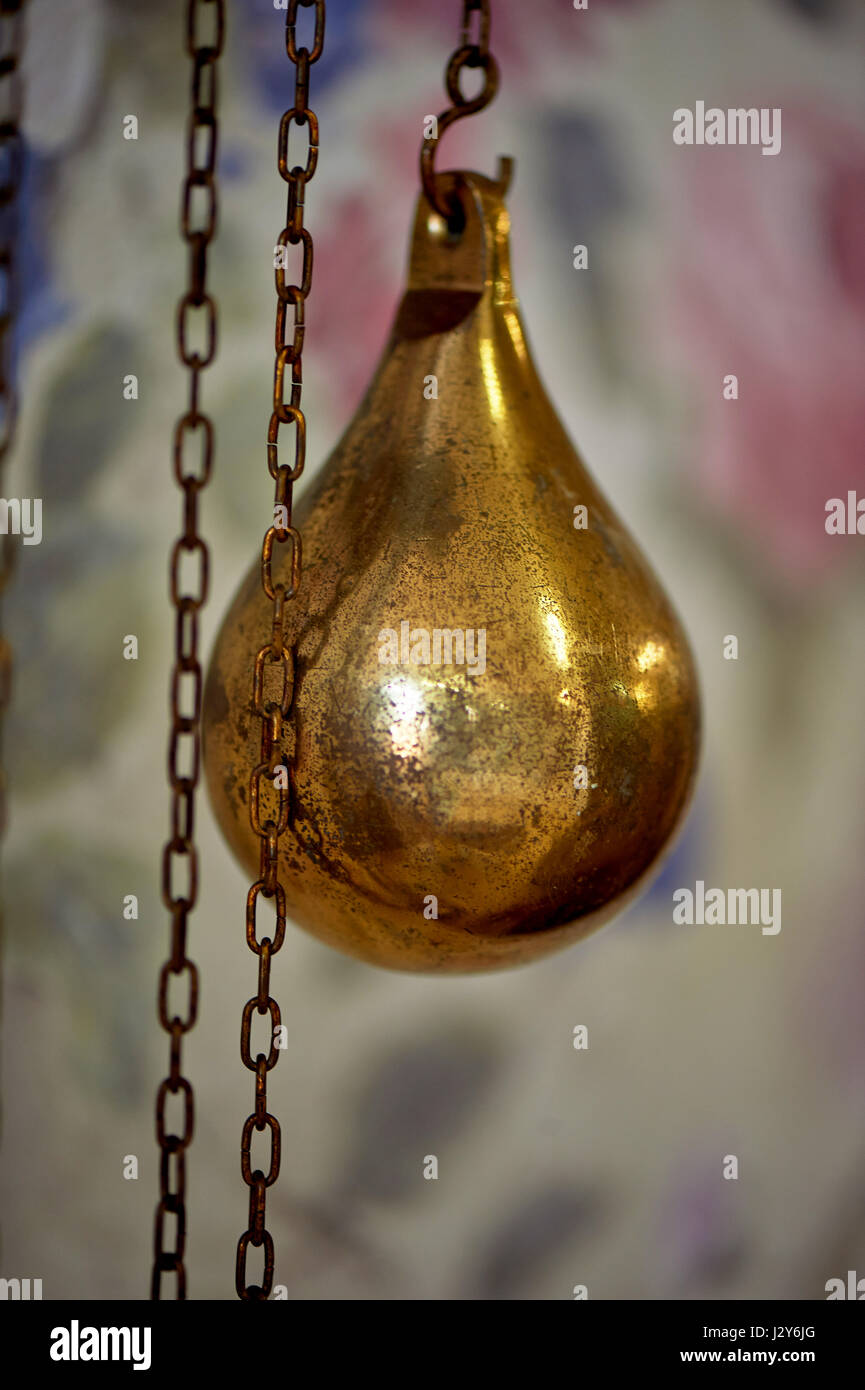 The weight or load on old retro clock on a chain. Close. Metal or ...
