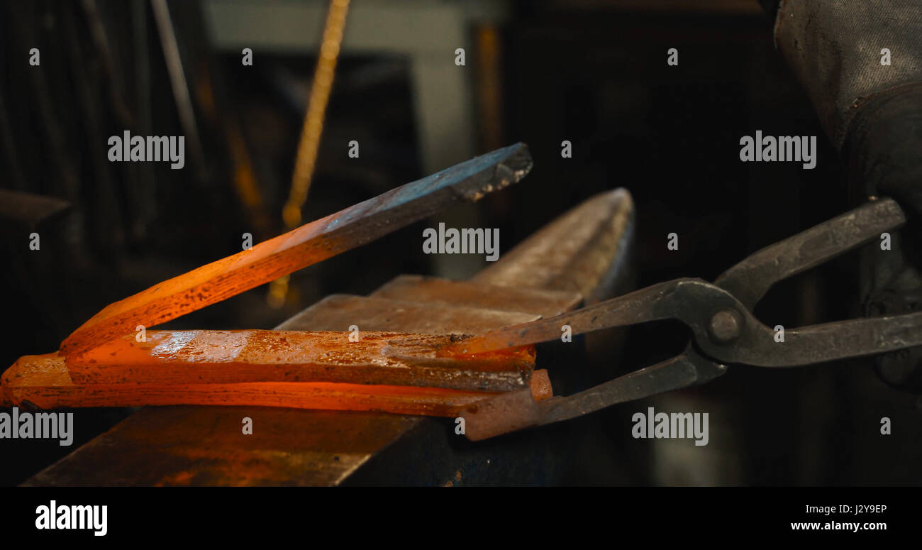 Rod hot iron on the anvil ready to be beaten Stock Photo - Alamy