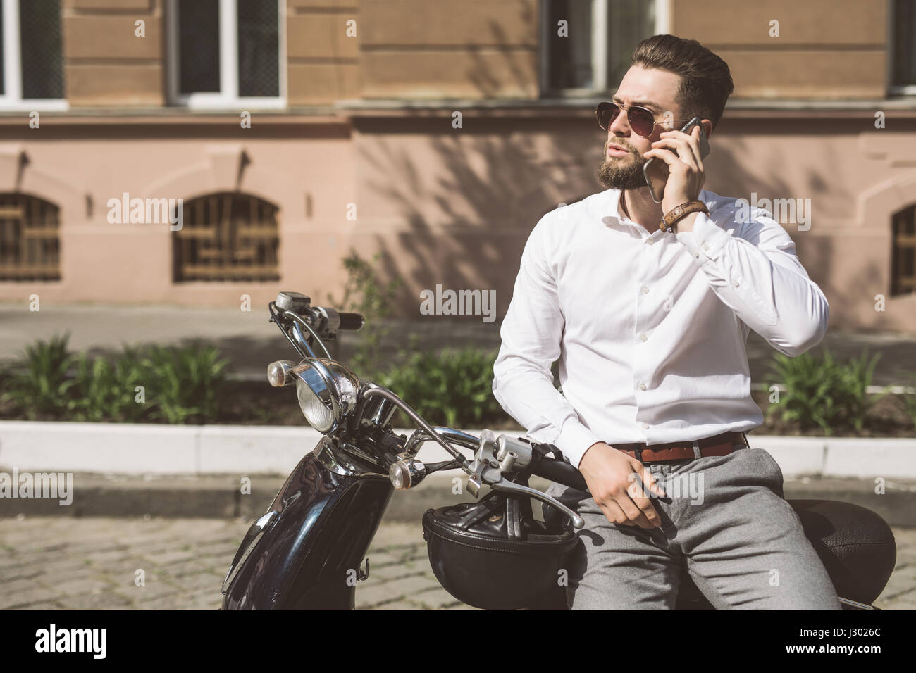 Handsome man sitting on the motorbike talking on the phone Stock Photo ...
