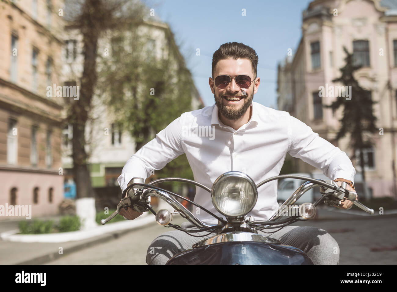 fashionable young man riding a vintage scooter in the street Stock ...