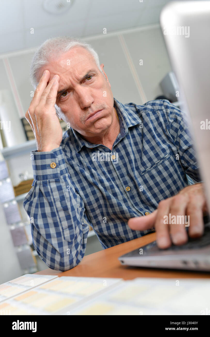 Frowning man on laptop Stock Photo - Alamy