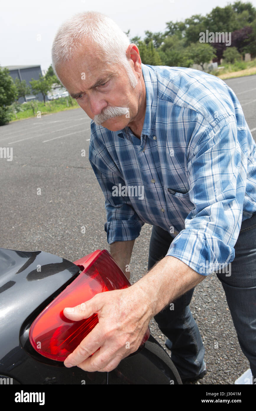 old man installs tail light on the vehicle Stock Photo - Alamy