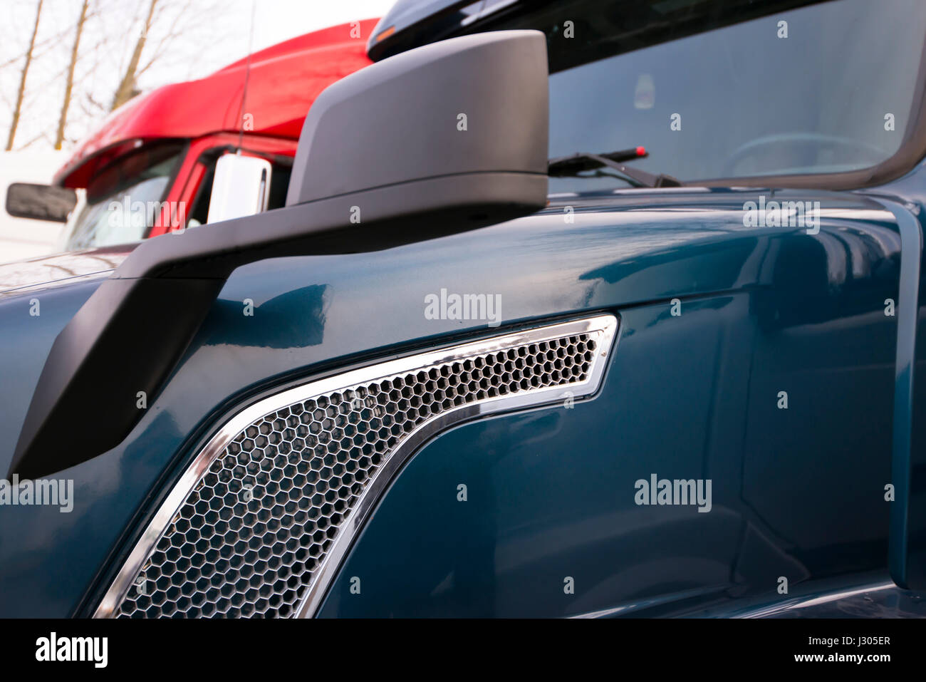 Close view of dark big modern rigs semi trucks with mirror and grille ...