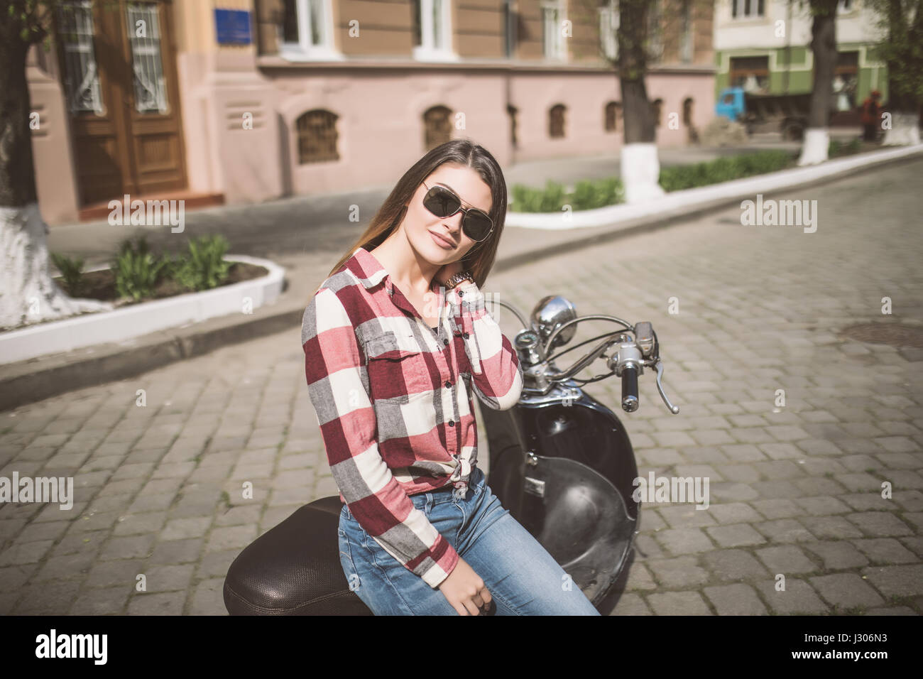 Young and beautiful woman riding scooter along the street Stock Photo ...