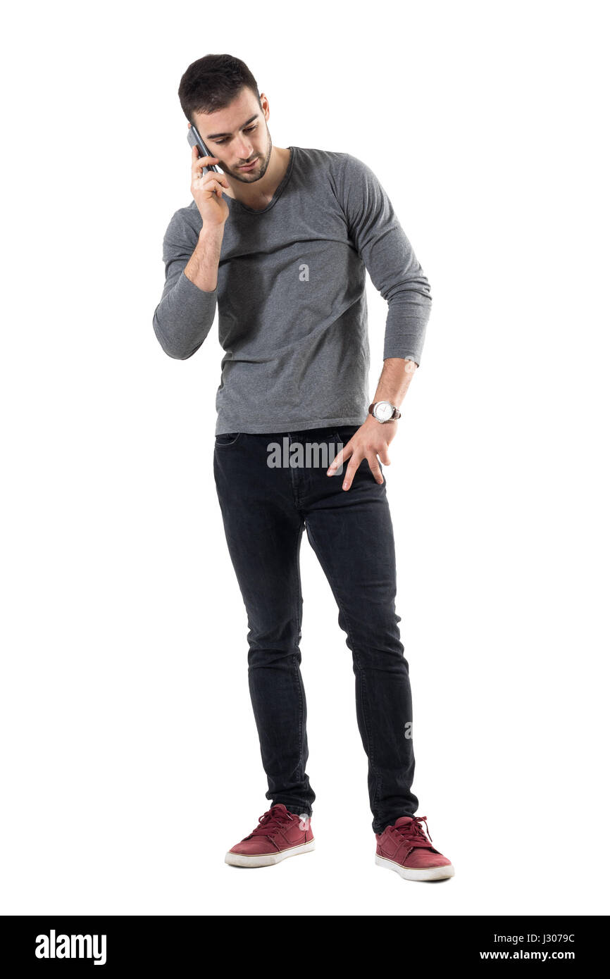 Serious young worried casual man talk on the phone looking down. Full ...