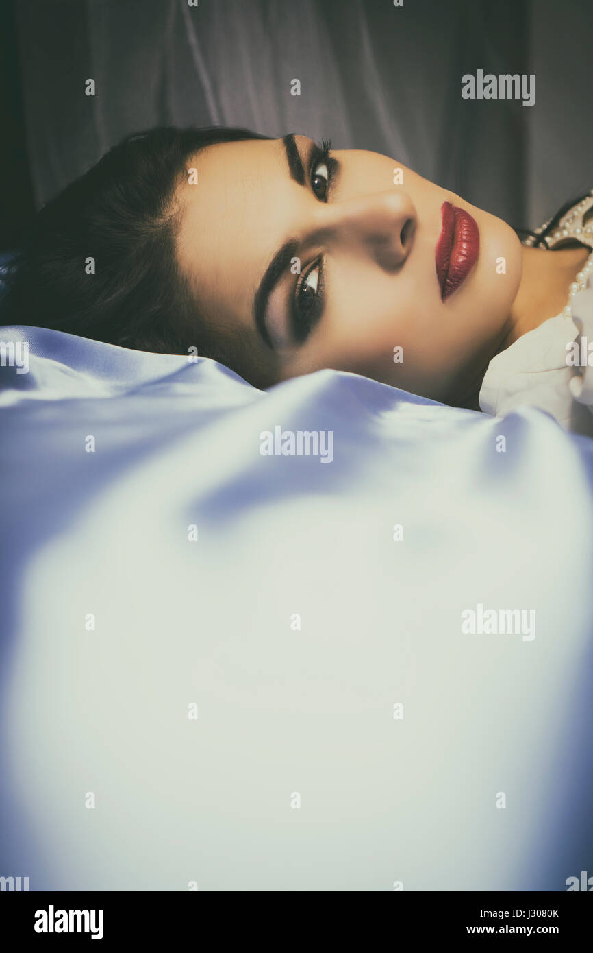 Alluring young woman laying down in bed staring Stock Photo - Alamy