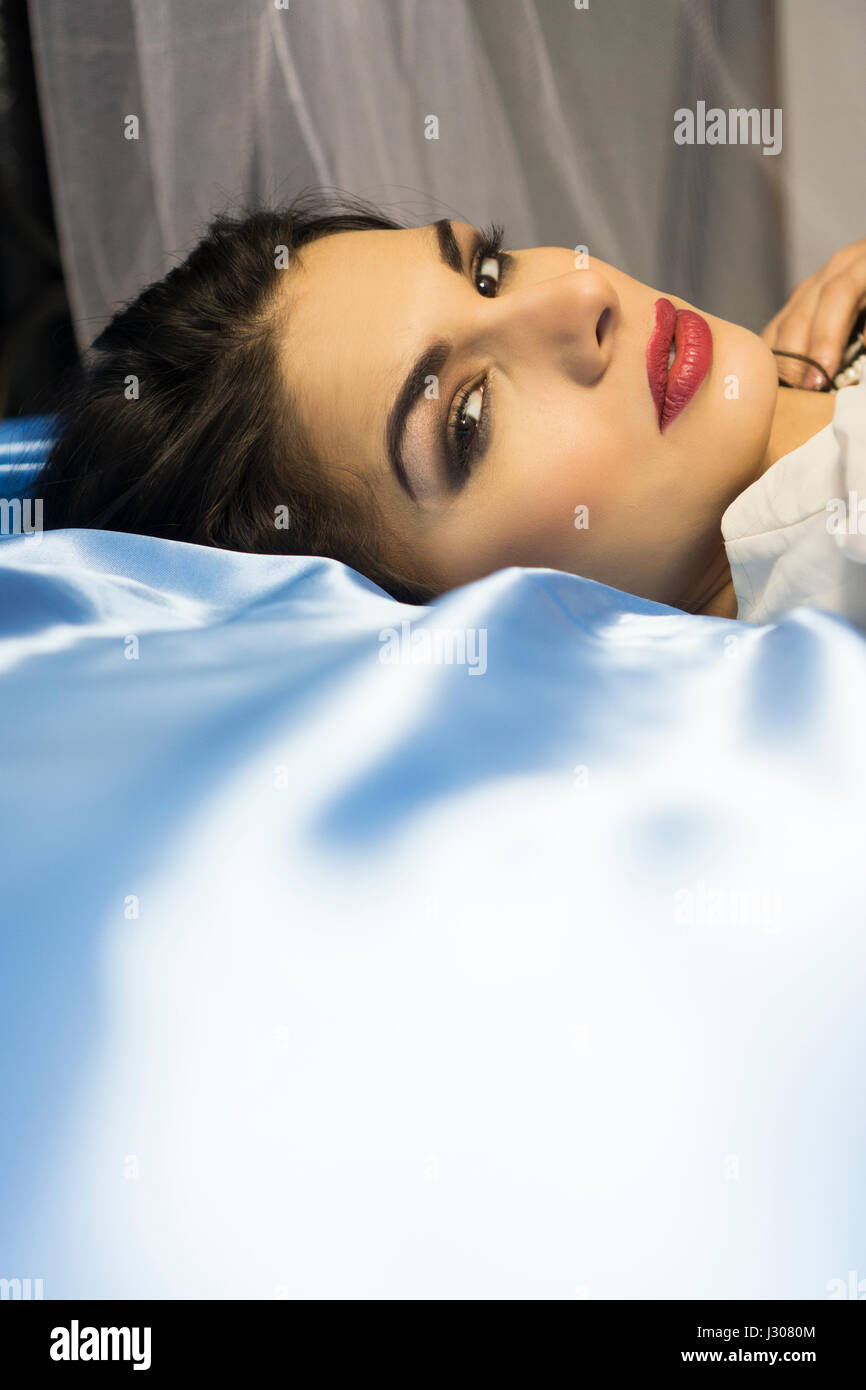 Alluring young woman laying down in bed staring Stock Photo - Alamy