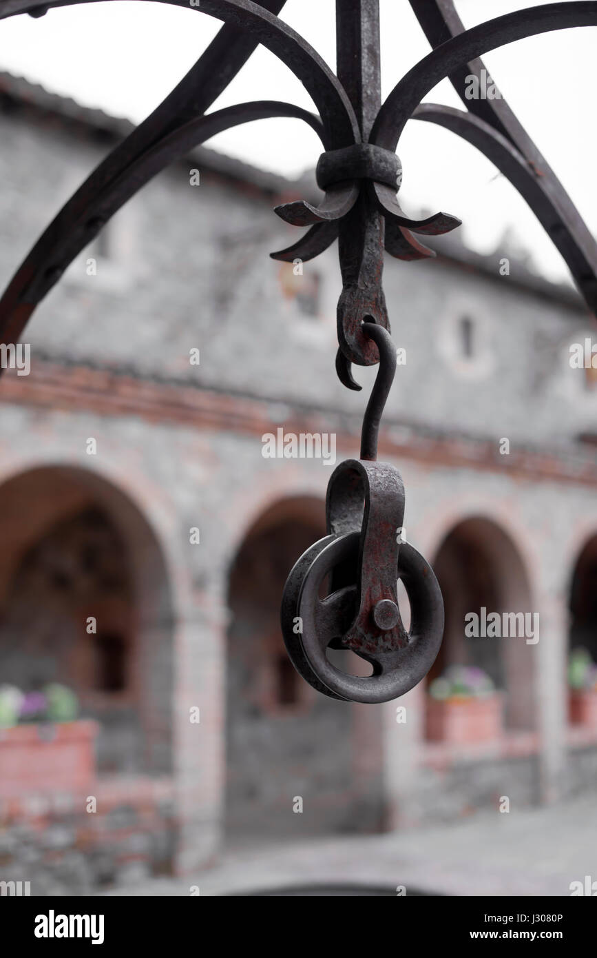 Old rusty metal block suspended from the arched wrought-iron grille ...