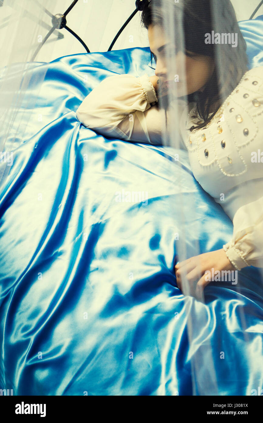 Sad young woman laying down in bed Stock Photo - Alamy