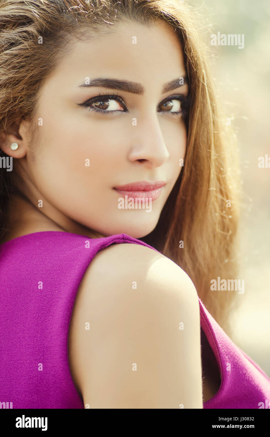 Beautiful young woman looking over shoulder outdoors Stock Photo - Alamy