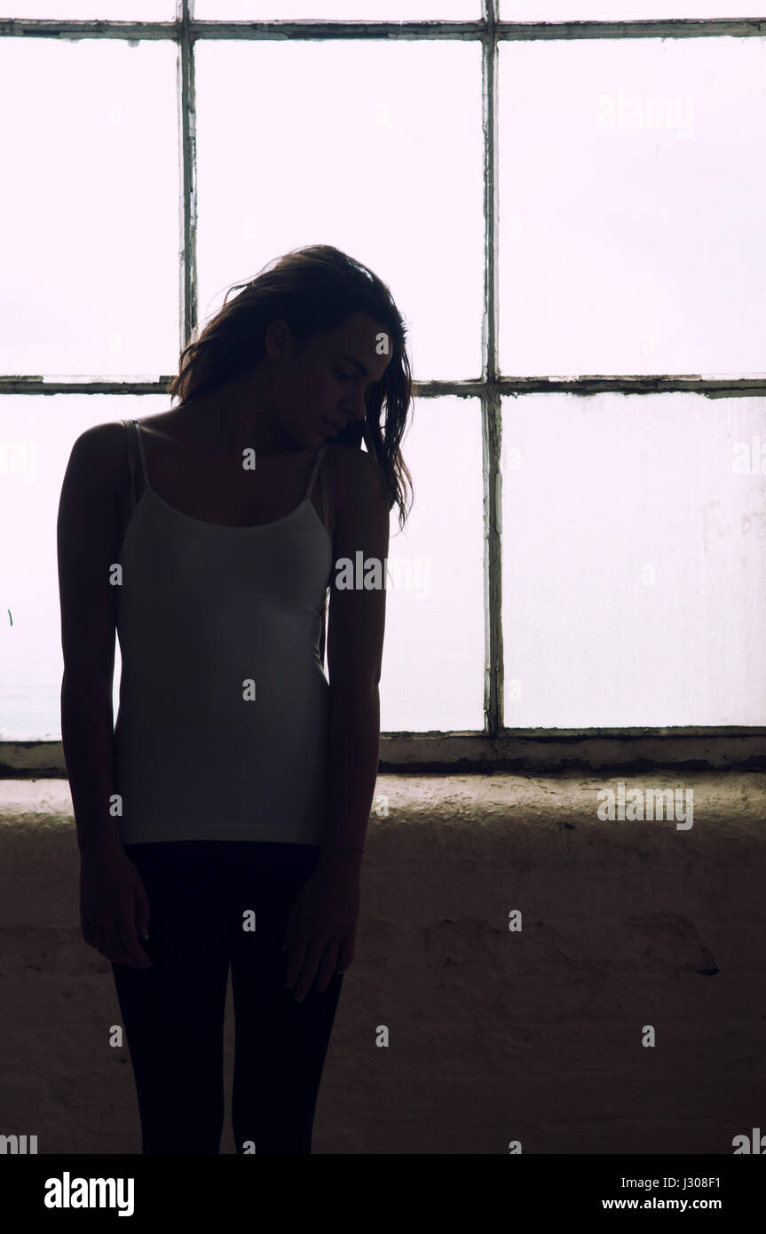 Young woman standing near the window Stock Photo - Alamy