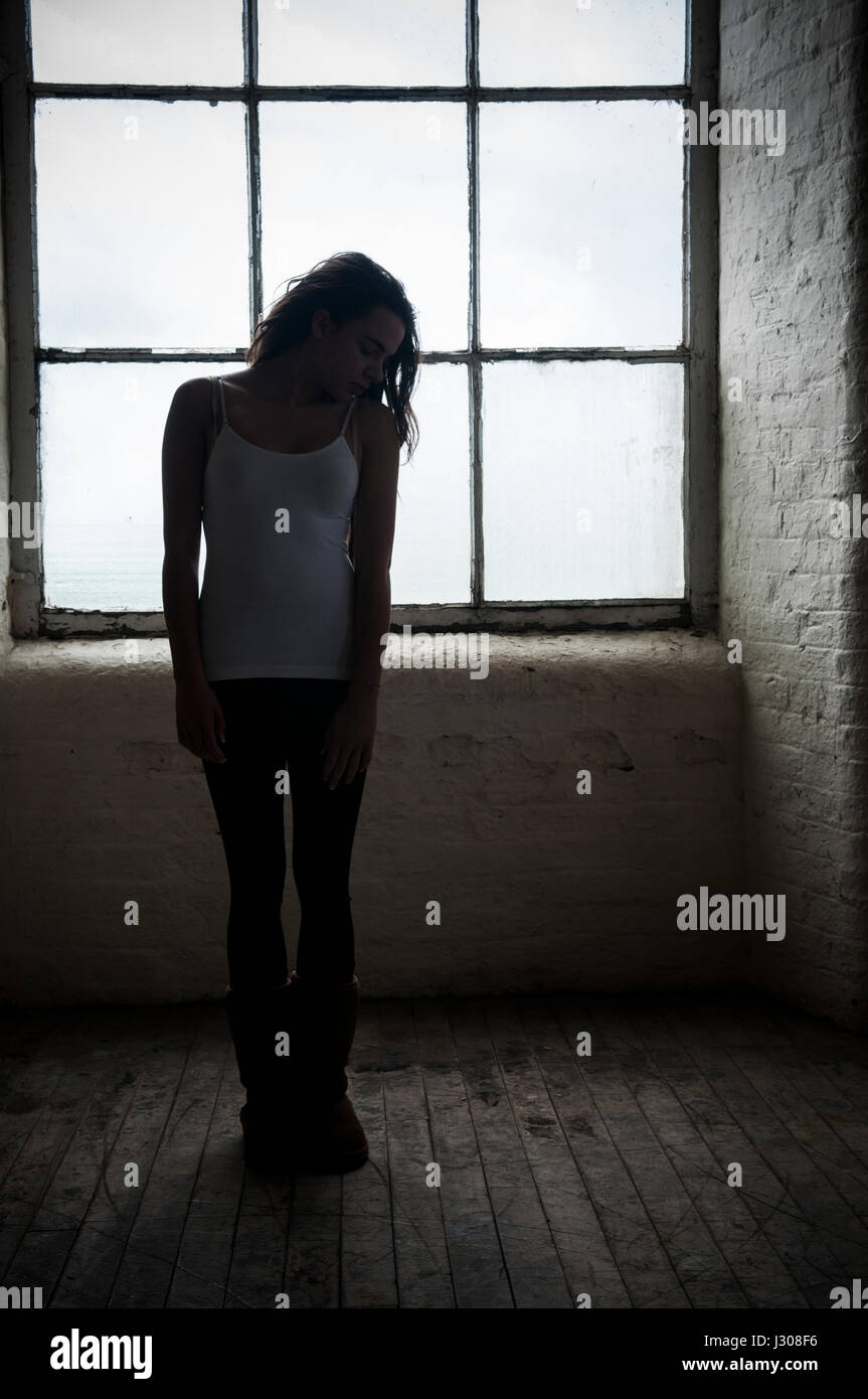 Young woman standing near the window Stock Photo - Alamy
