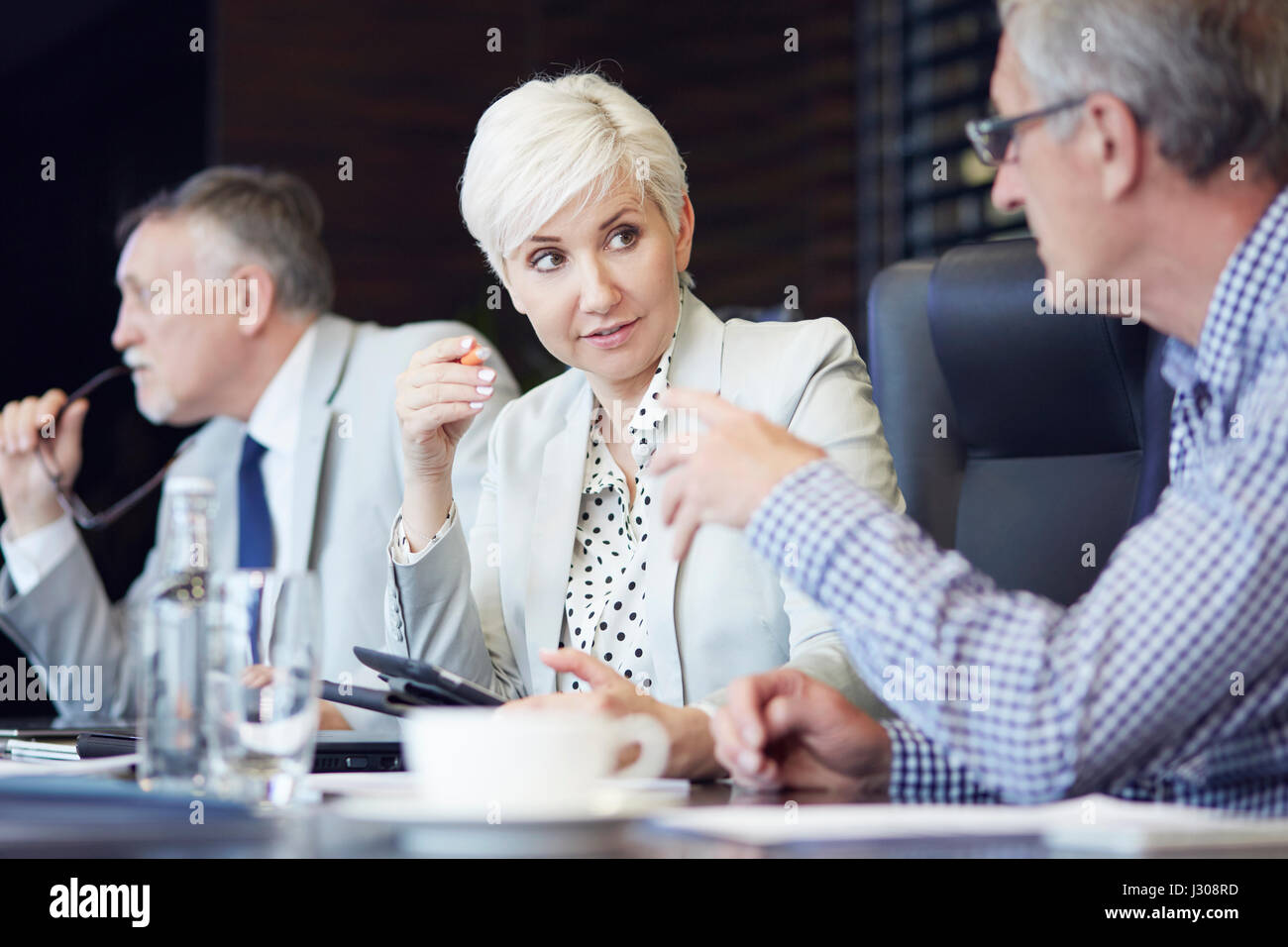 Group of business people huddled around table working Stock Photo - Alamy