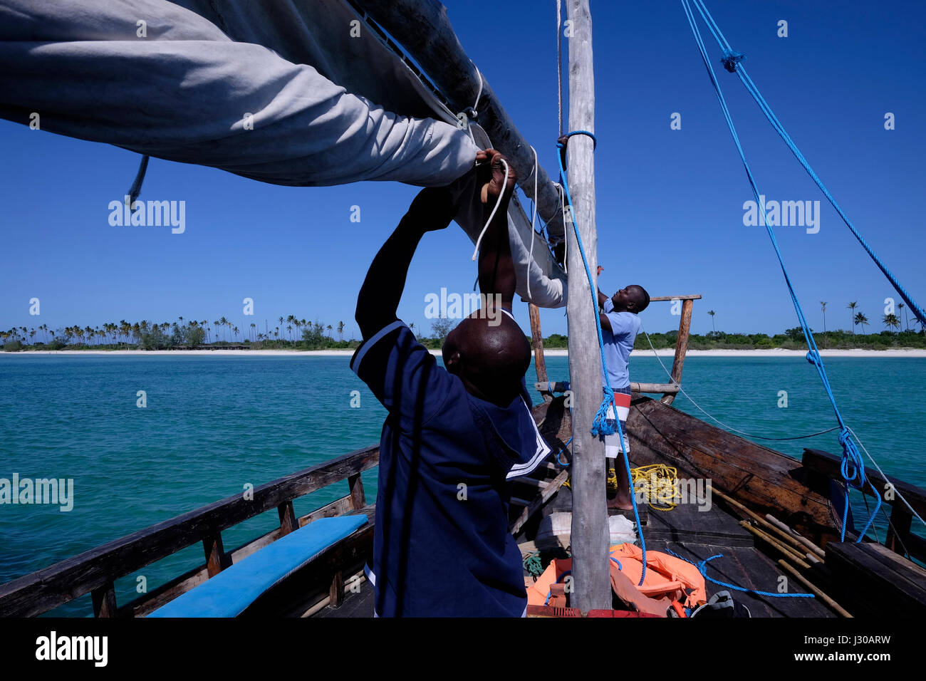 Boat crew trimming sails in a Dhow traditional sailing vessel at the ...