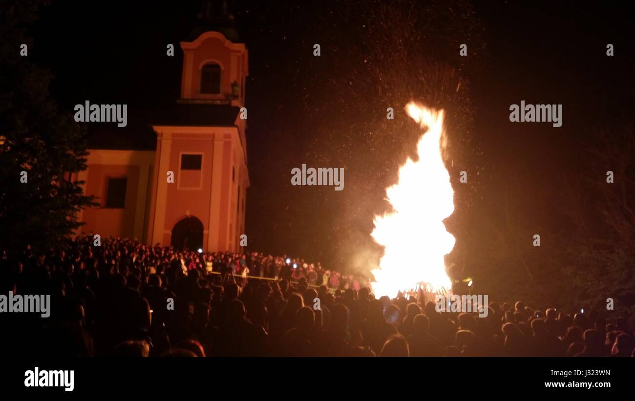 Big vivid traditional bonfire with numerous group of people near church ...
