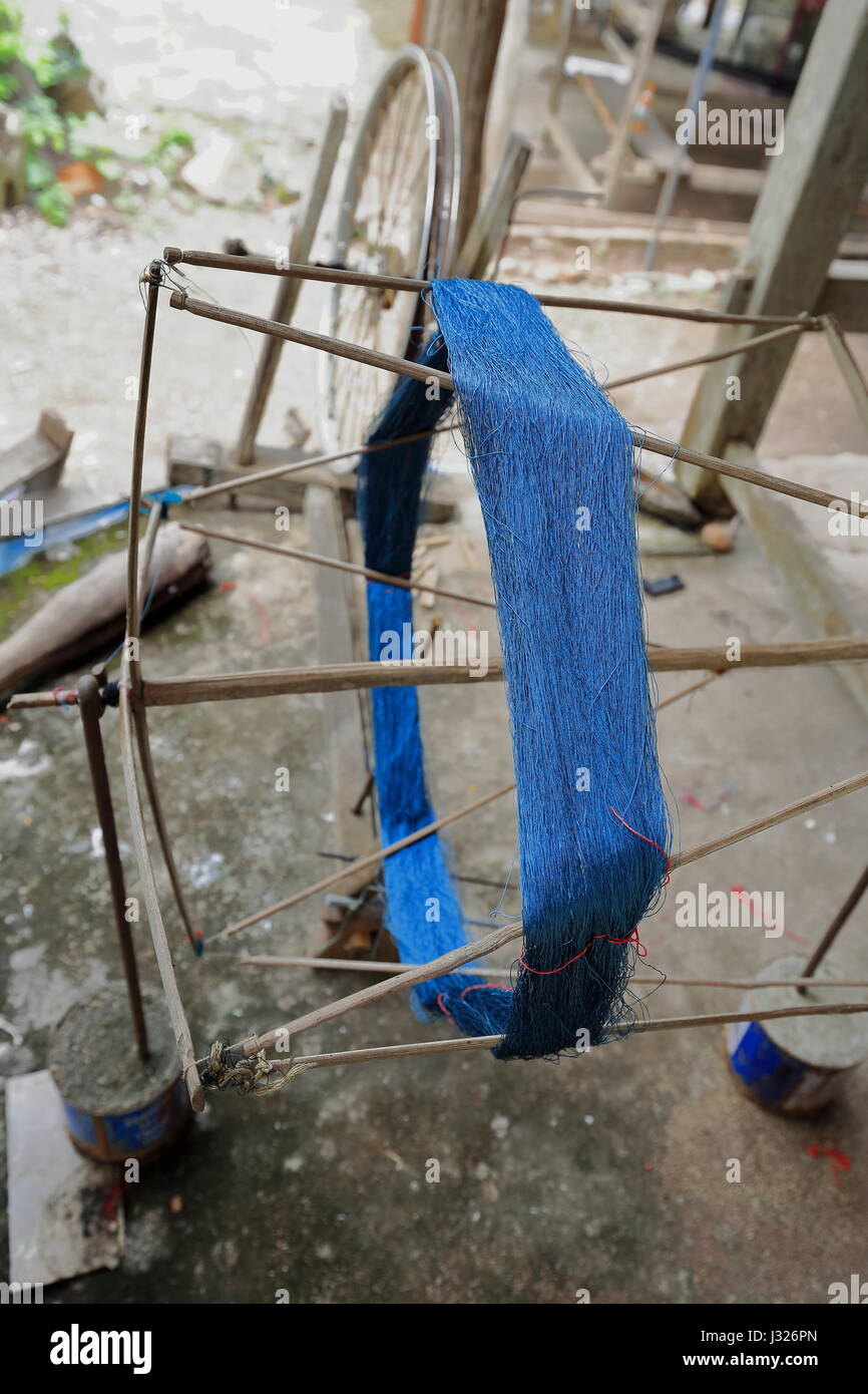 Artisanal double spinning wheel with blue thread. Ban Xang Khong ...