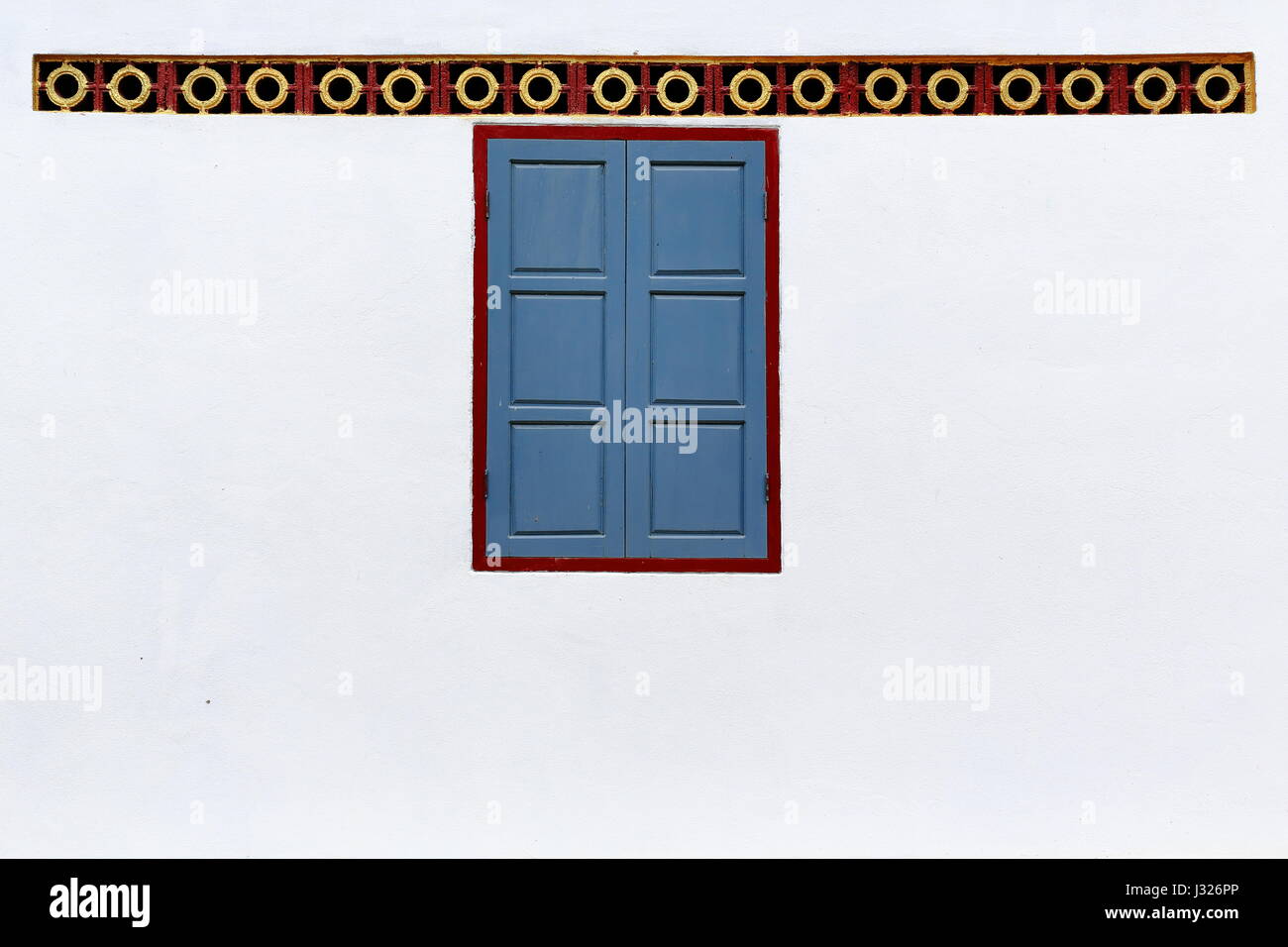 Closed blue shutters of window with maroon windowframe on the ...