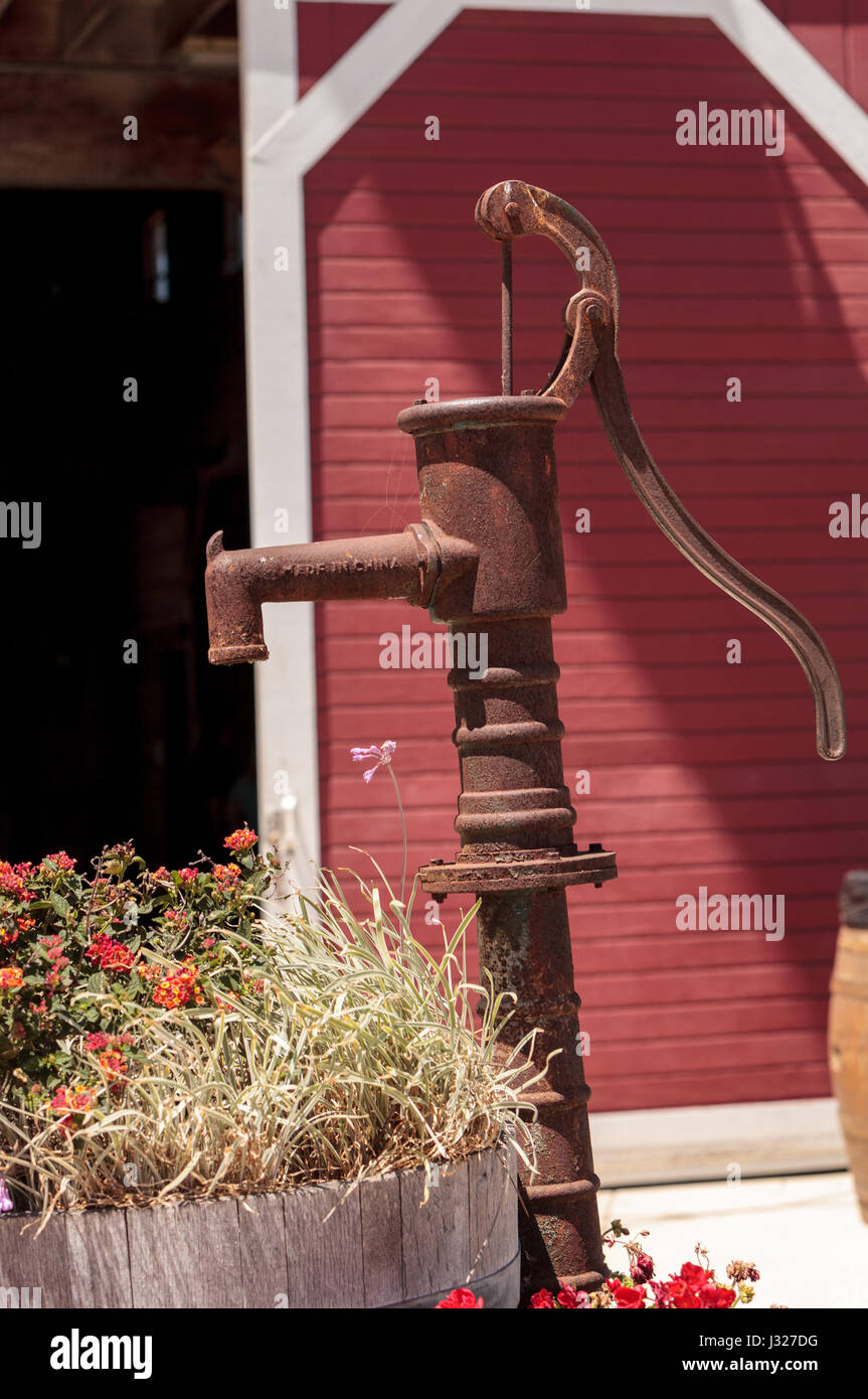 Well water pump on a farm in summer with flowers and a barn Stock Photo ...