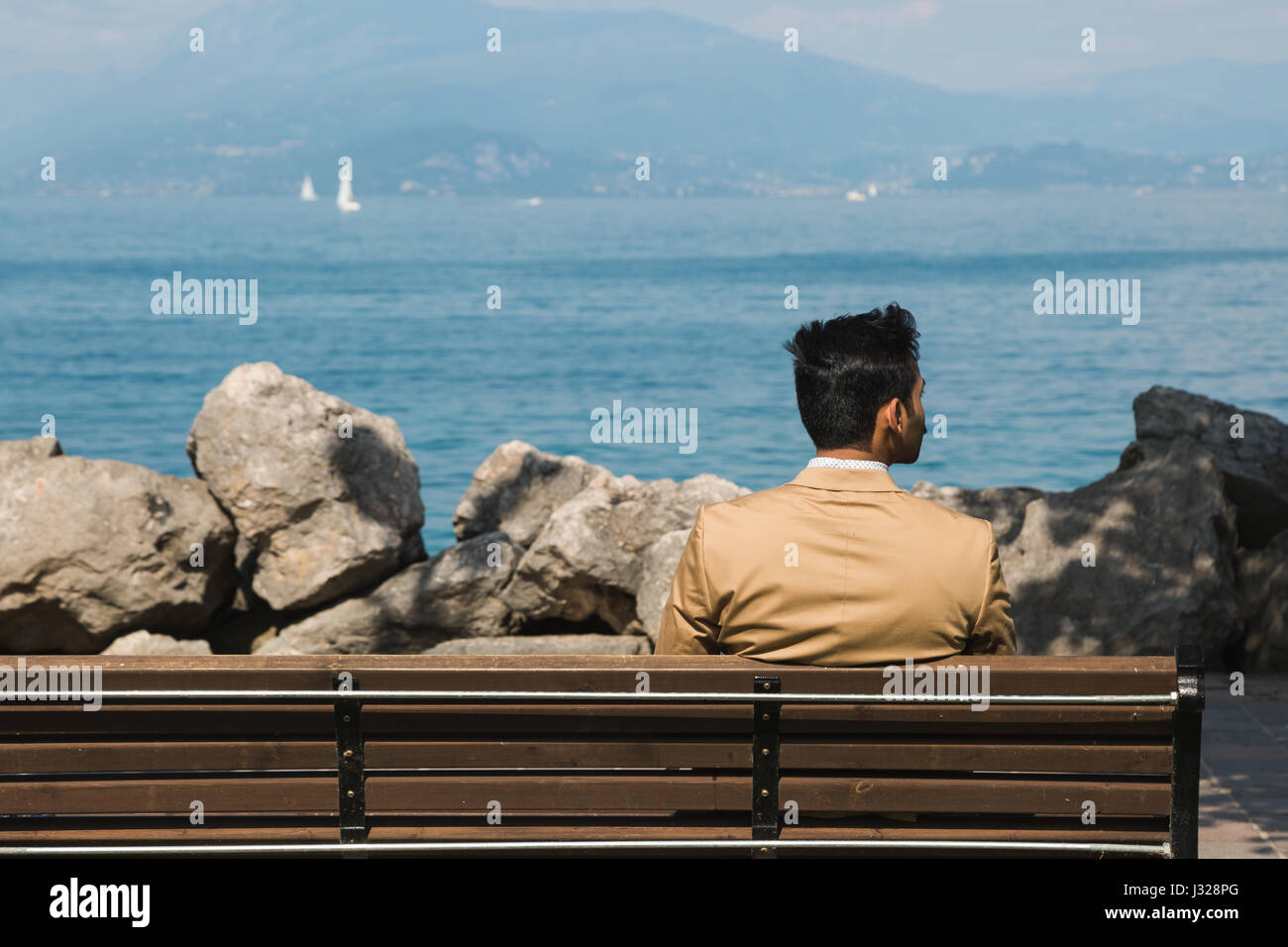 Man sitting on a bench and looking at the horizon. Concept of solitude ...