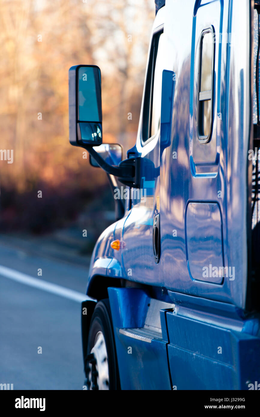 Cabin of blue big rig on the road with reflaction of sun and brown ...