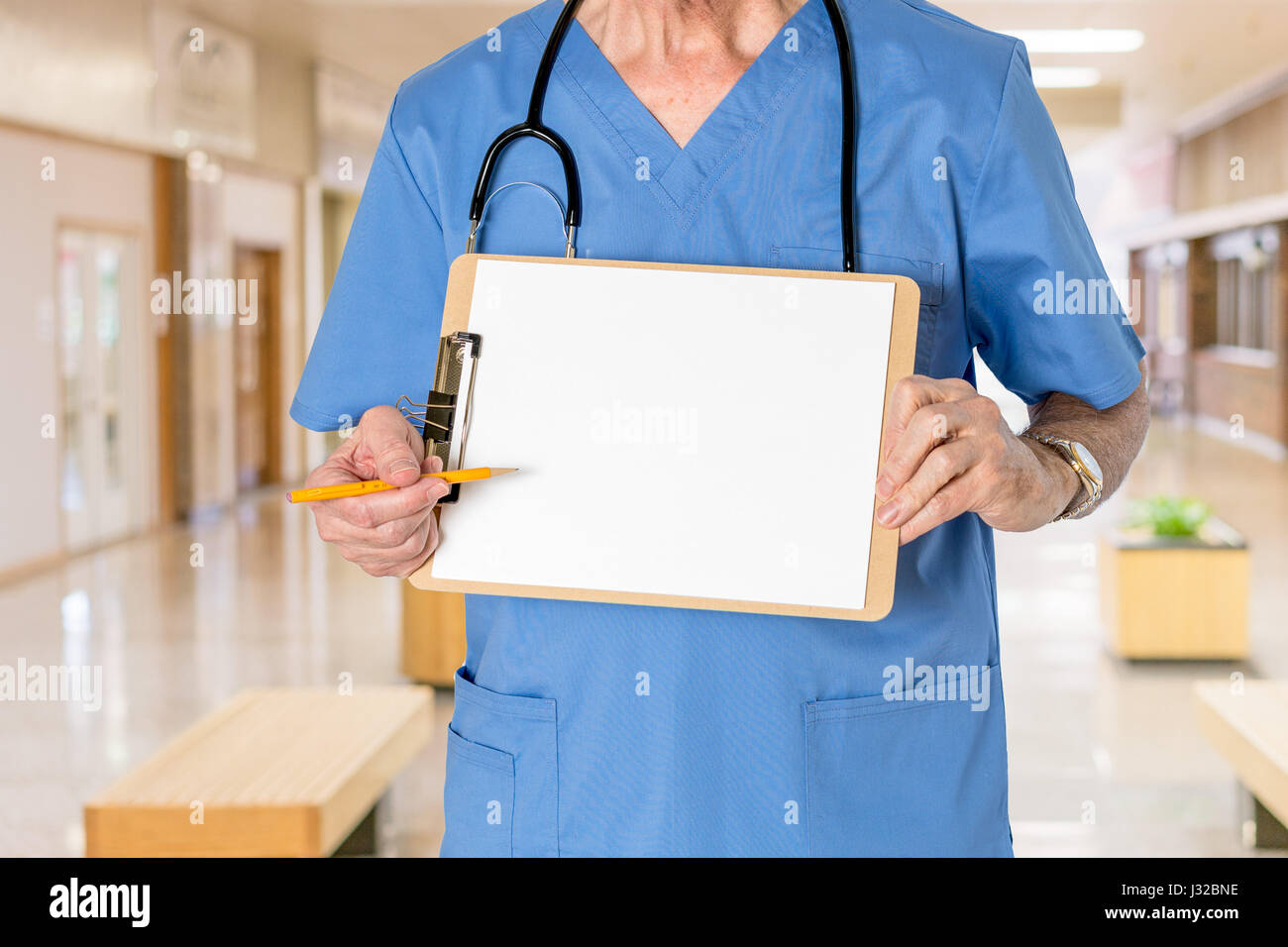 Doctor with stethoscope in medical scrubs holding blank clipboard for ...