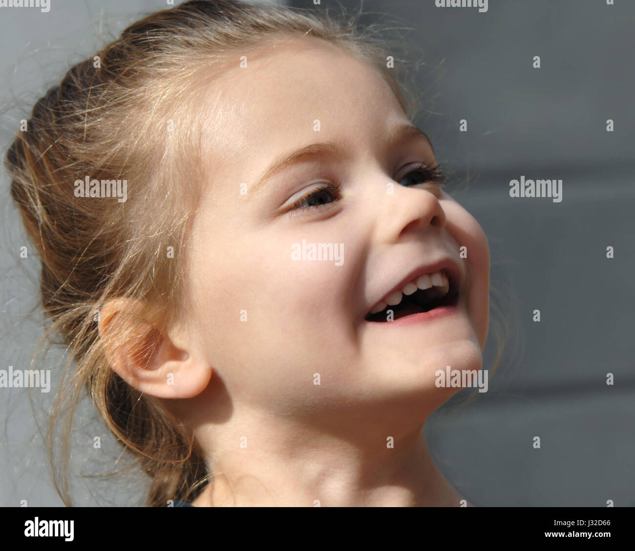 Little girl laughing responds to situation. She has long hair and is ...