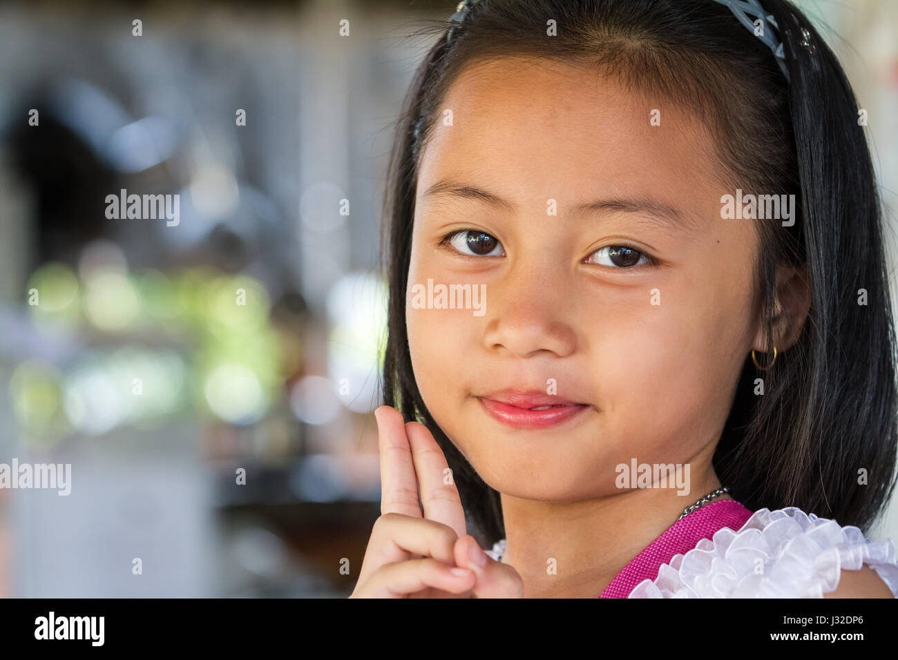 Thai girl poses with a nice smile and two fingers Stock Photo - Alamy