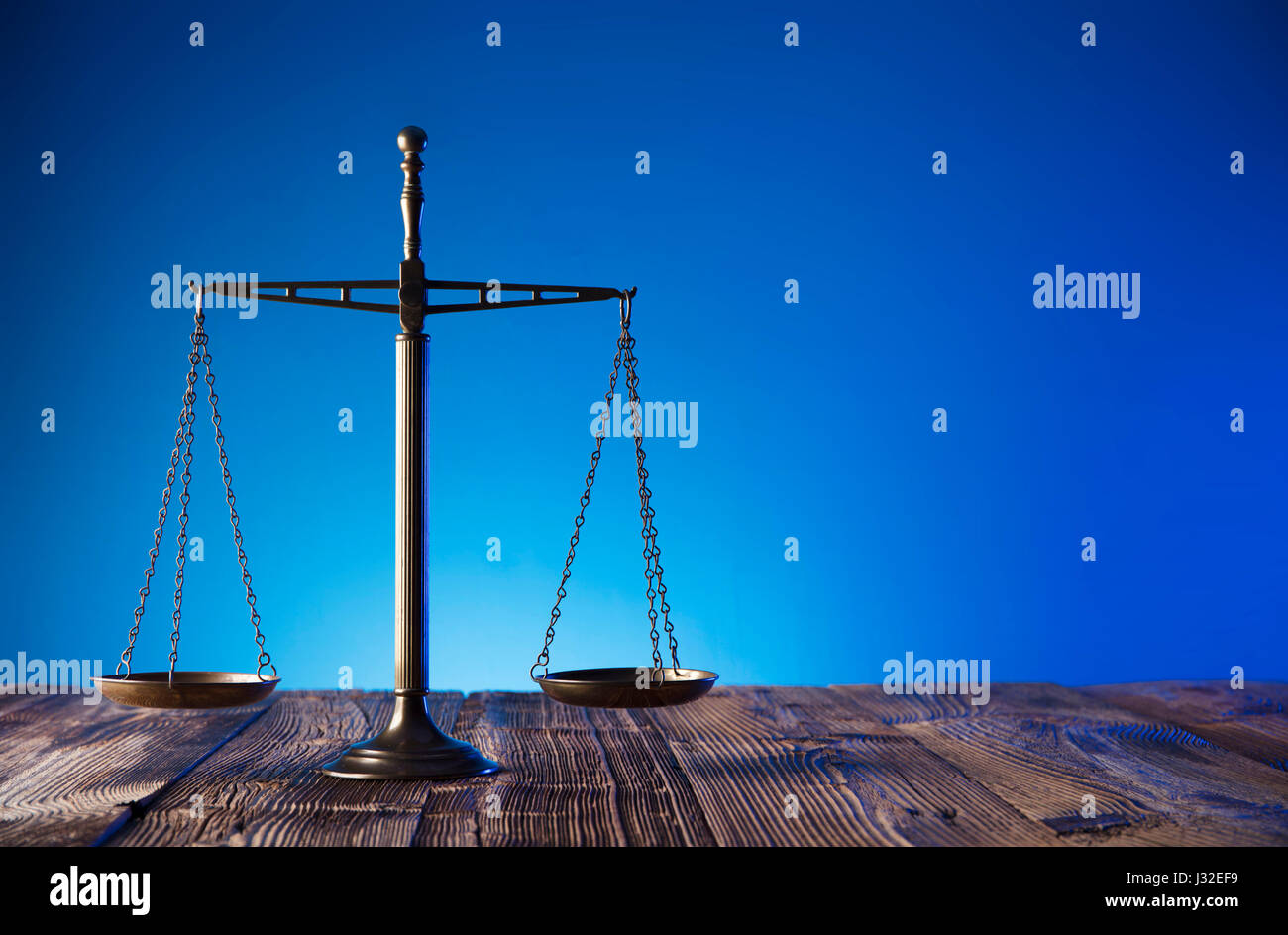 Scale of justice on old wooden table and blue background. Law theme and ...