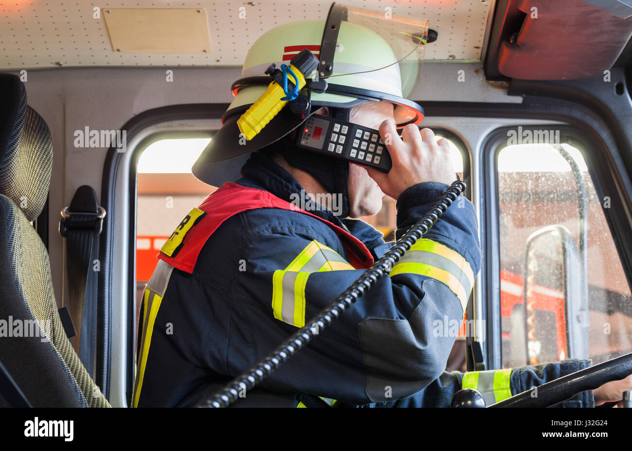 German firefighter drives in a fire truck in action and used a walkie ...