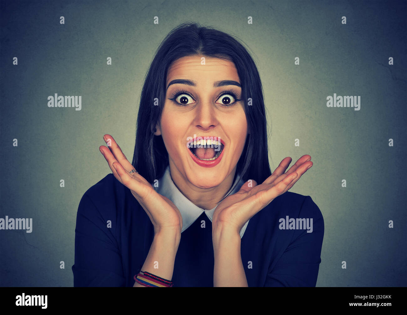 Surprised young woman shouting over gray background. Looking at camera ...