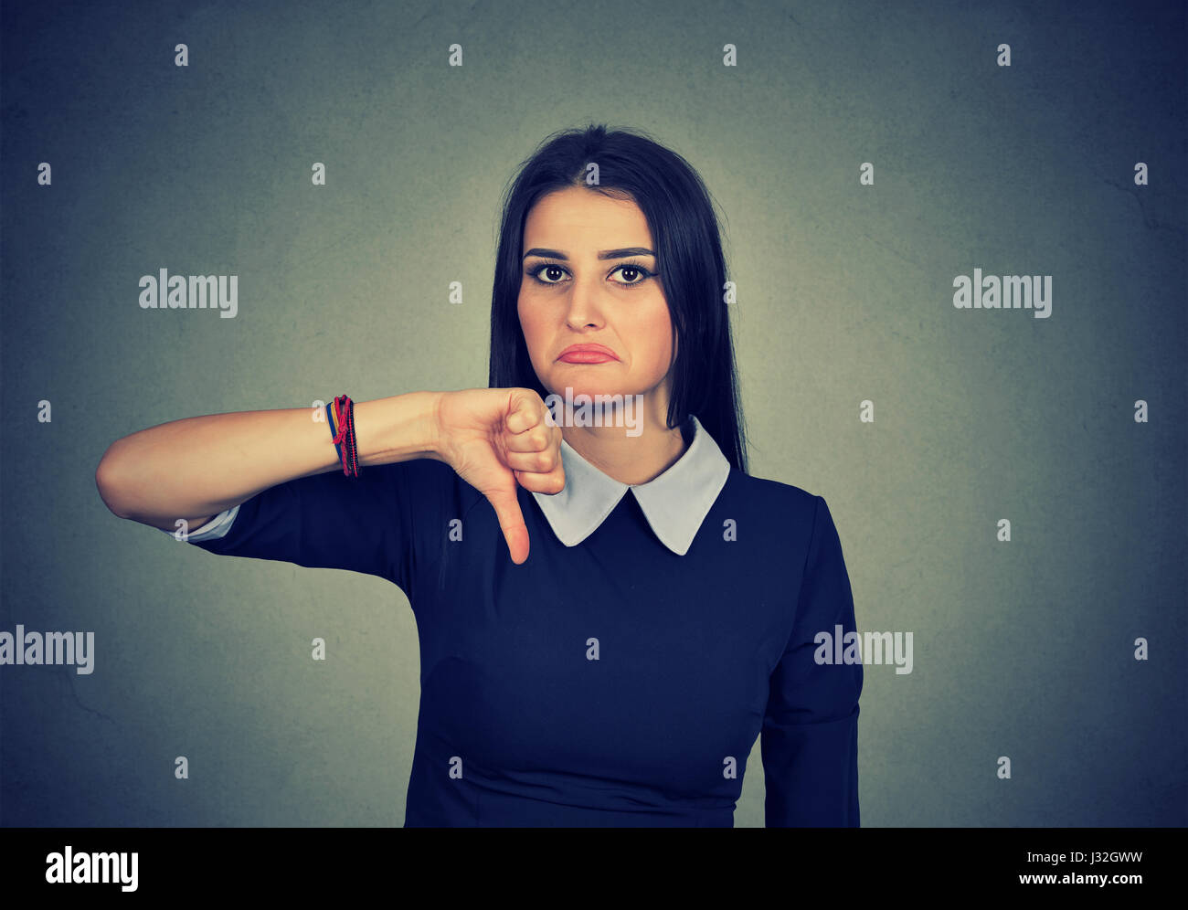 Unhappy woman giving thumb down gesture looking with negative ...