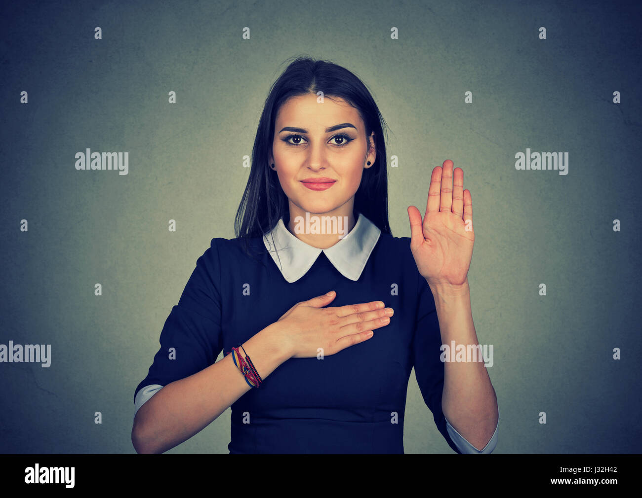 Young woman making a promise isolated on gray wall background Stock ...