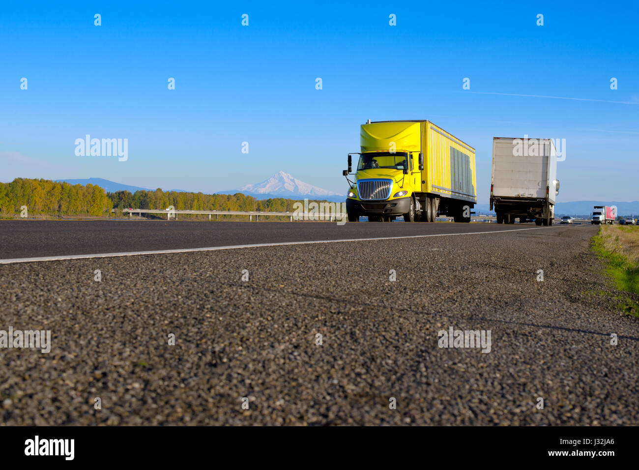 Modern bright yellow semi truck with yellow trailer on the scenic road ...