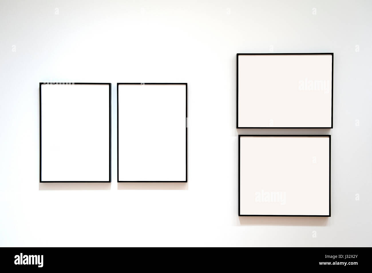 Four blank frames on a white wall Stock Photo - Alamy