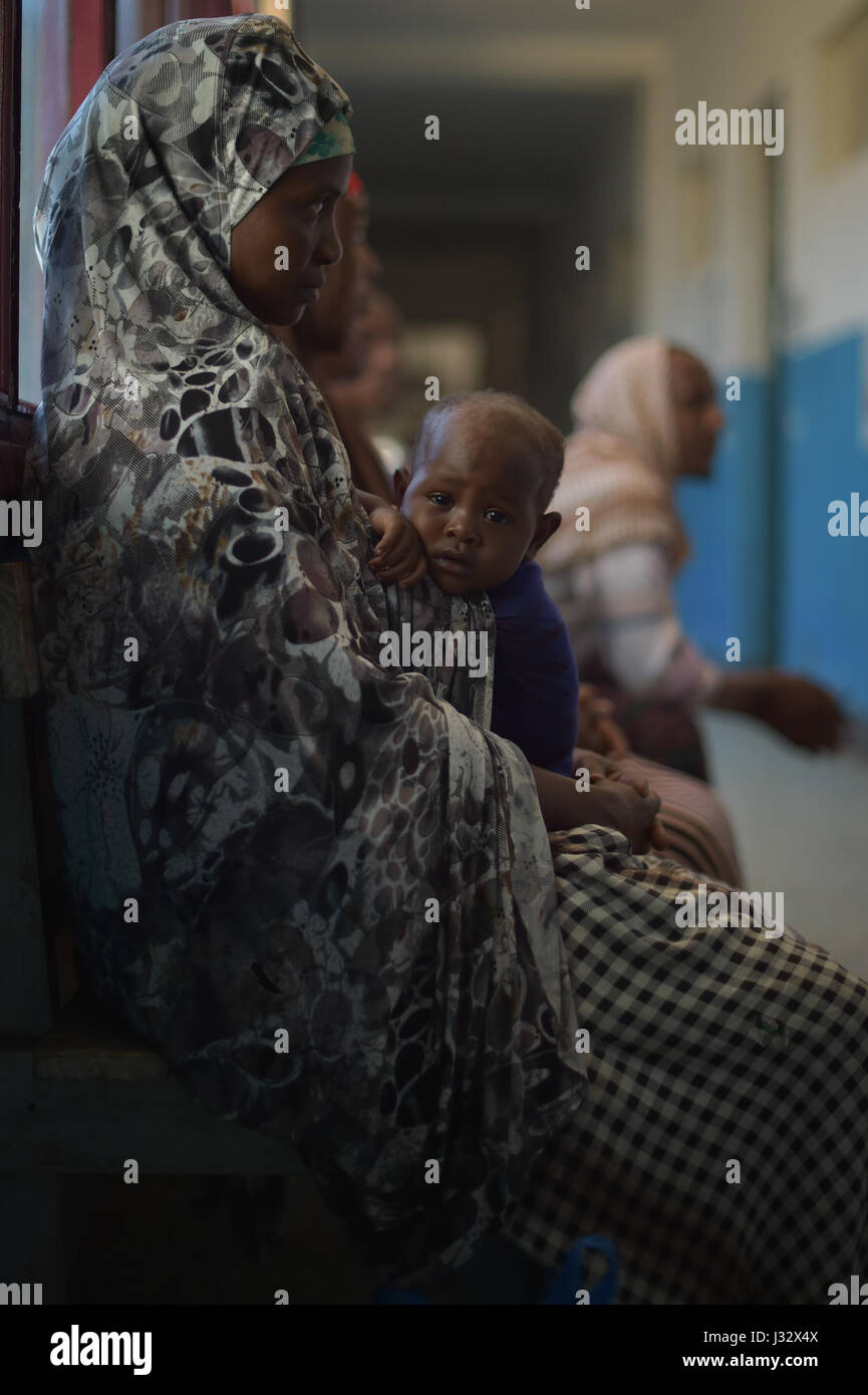 A malnourished child sits on his mother's lap at Banadir hospital in ...